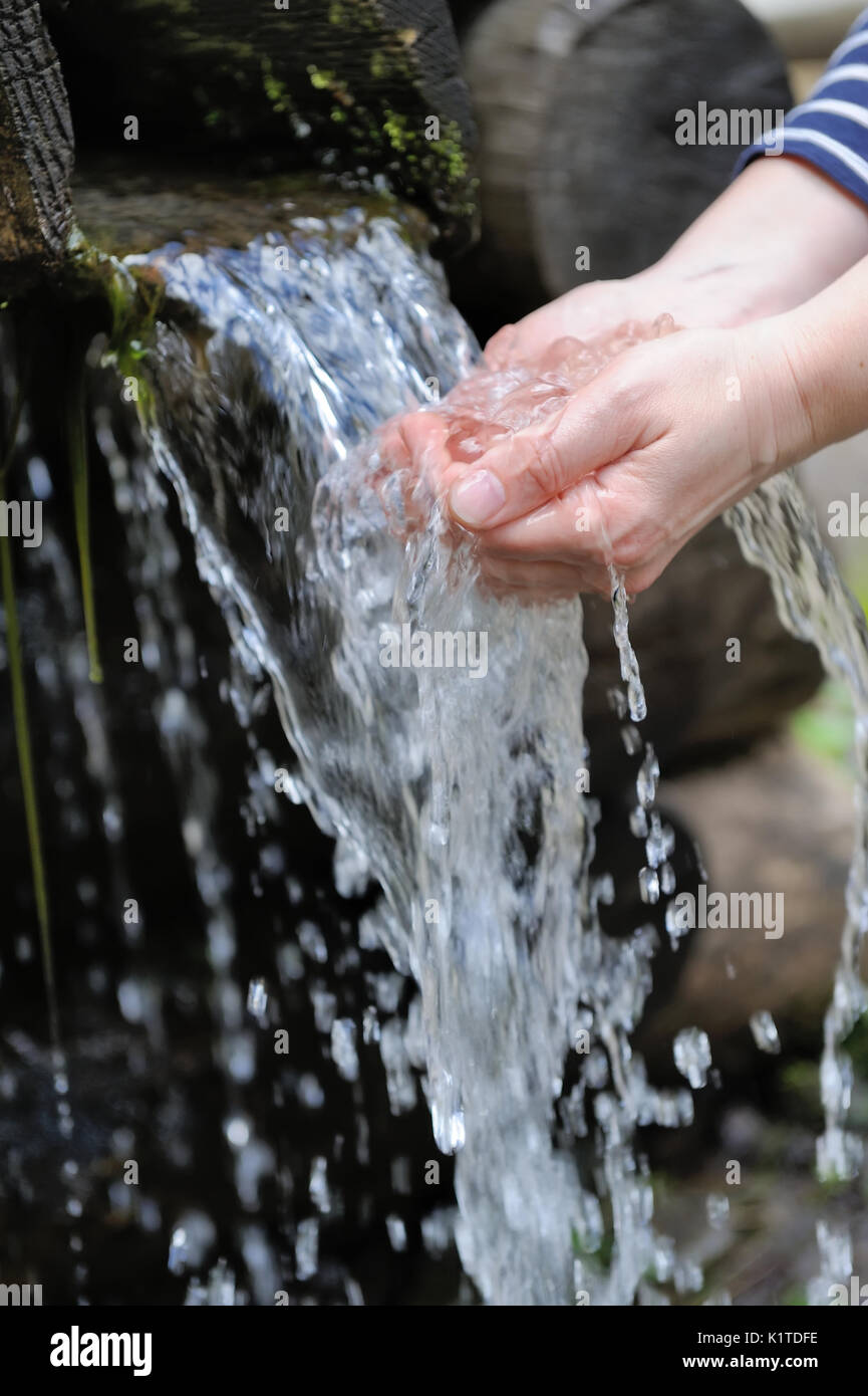 Water pouring in woman hand on nature background Stock Photo - Alamy