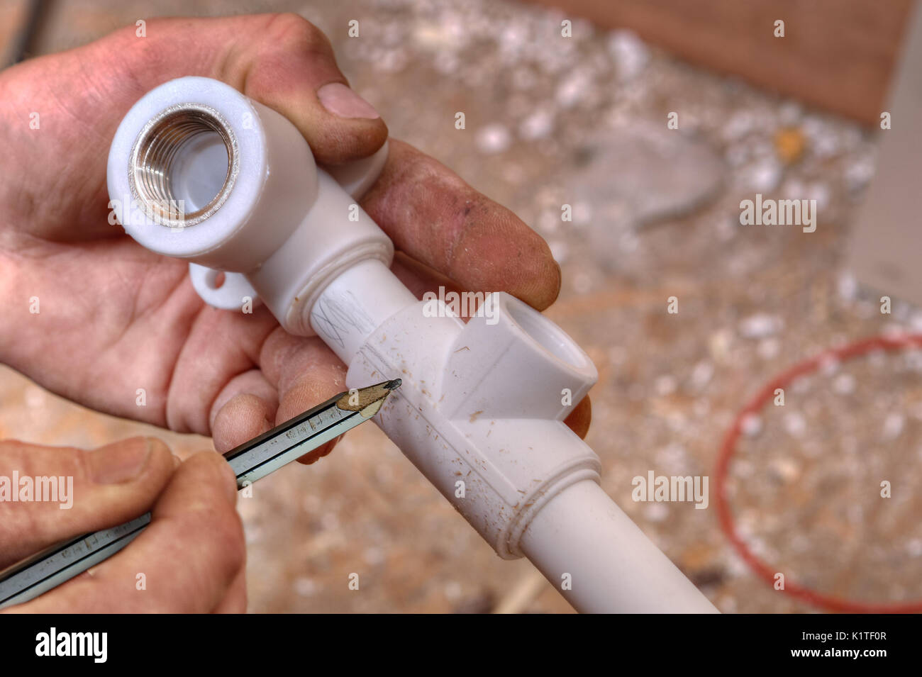 The plumber makes markings on plastic fittings using a pencil, close-up ...