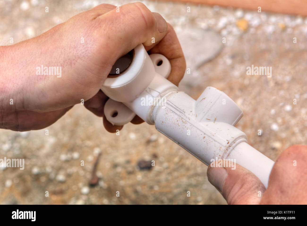 The plumber connects parts of the plastic water pipe using fittings ...