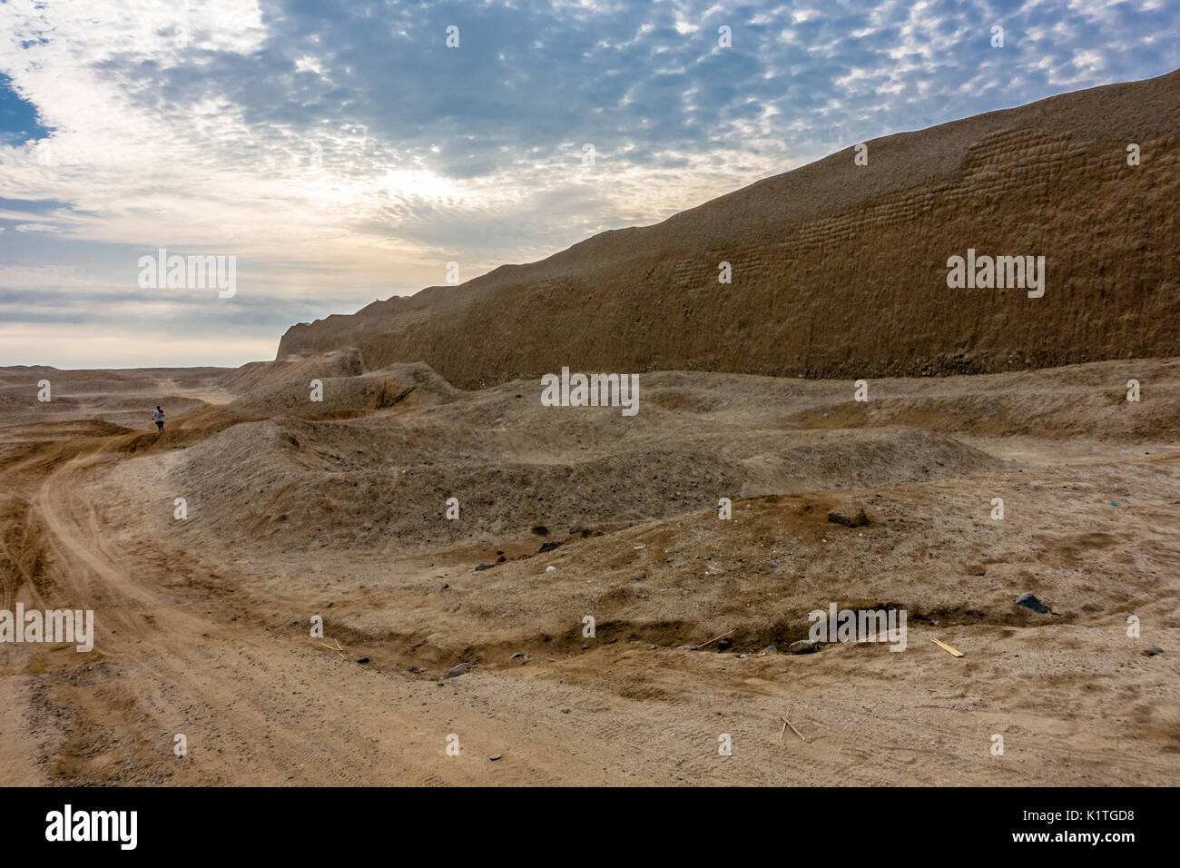 A young woman running in the desert by the walls of the Chan Chan ...