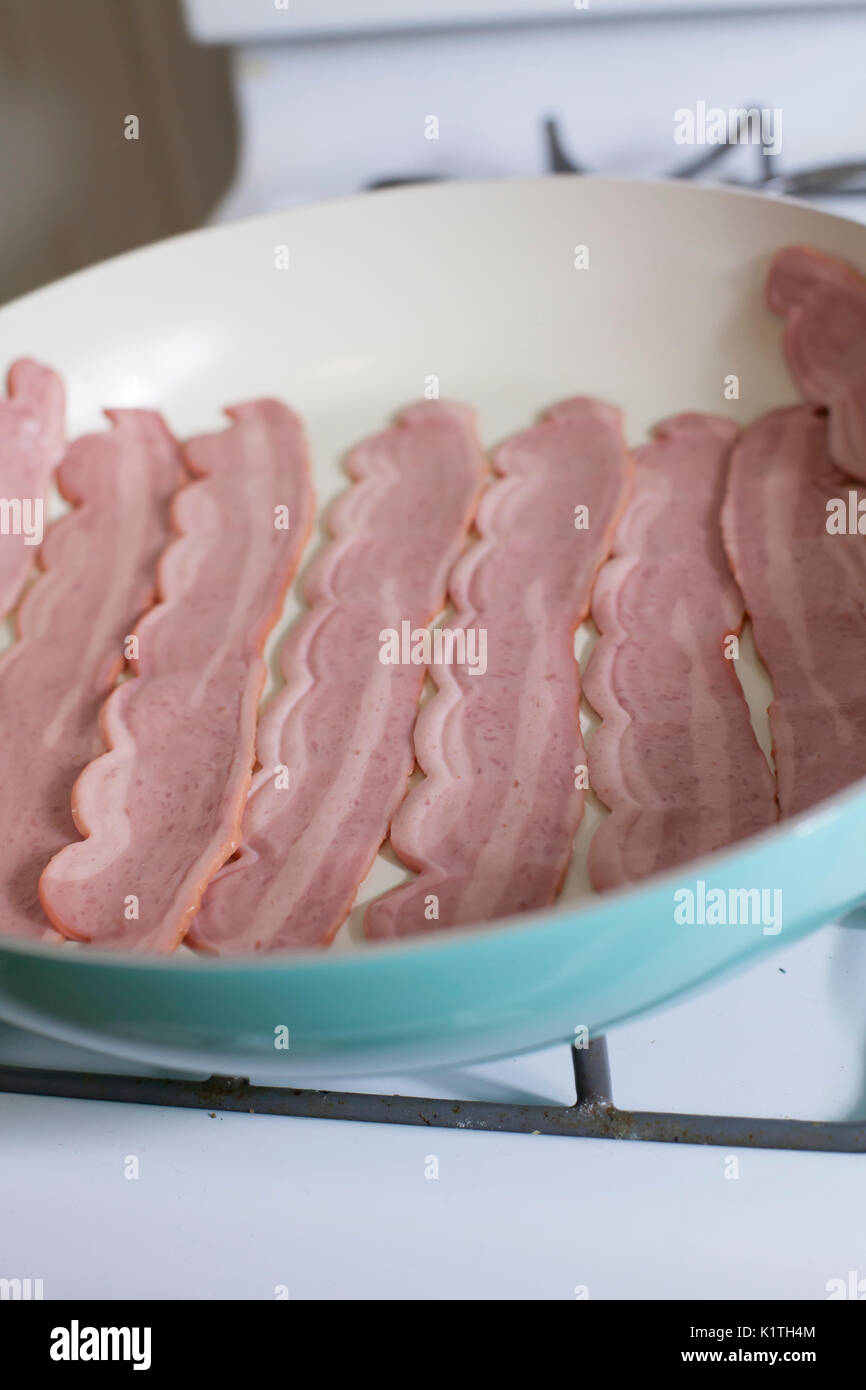 Raw bacon set to fry in a pan Stock Photo - Alamy