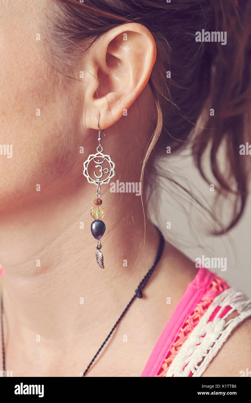 Beautiful earring with om symbol and ethno beads Stock Photo - Alamy