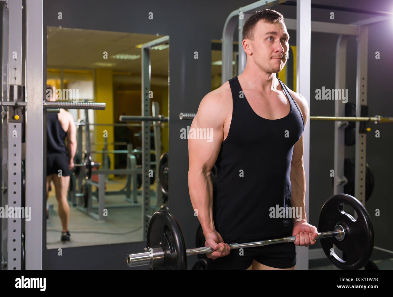 Muscular man with pulling up barbell in fitness training class indoors ...