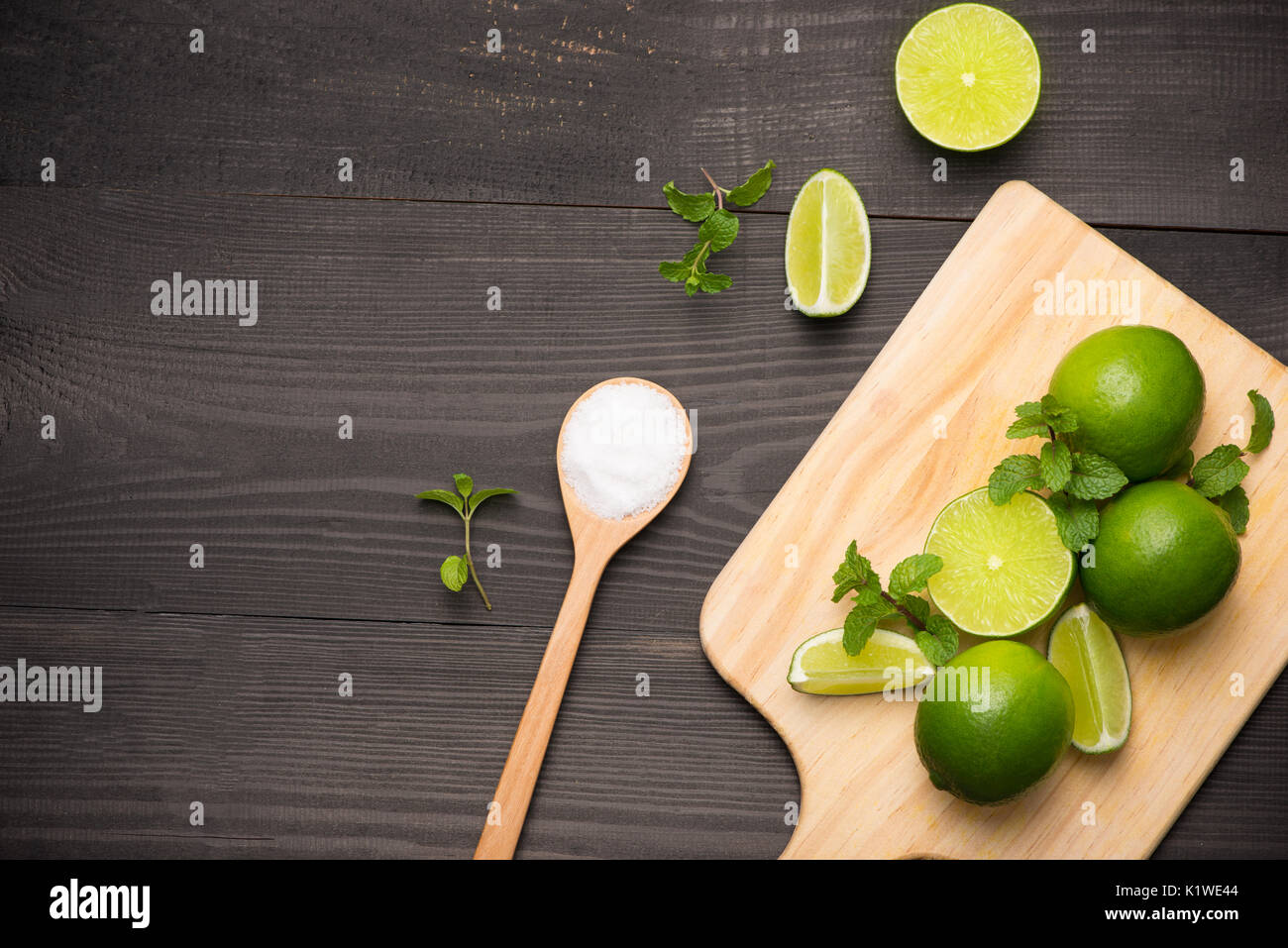 Fresh limes on cutting board on wooden table with spoon of salt. Top ...