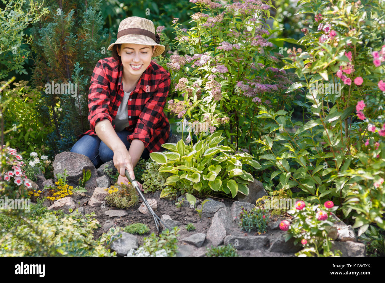 young woman gardener care of flowers in the garden. Girl weeding weeds ...