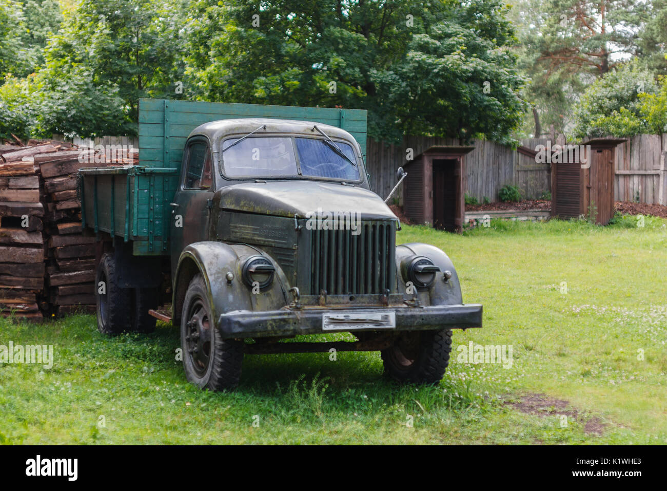 Ancient Soviet car in green meadow and old abandoned wooden outdoor ...