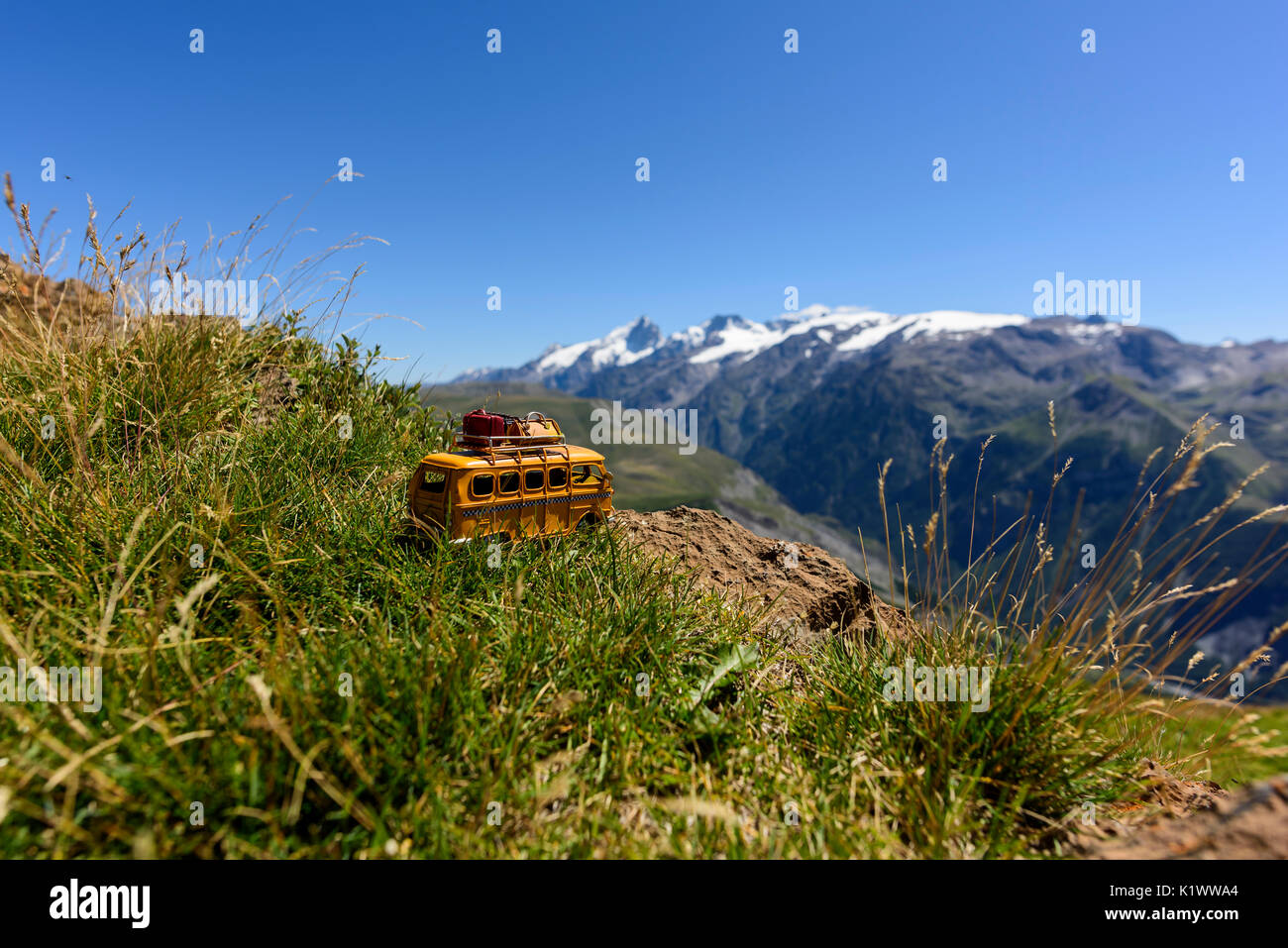 Hippies Minivan (RV camper van toy) on a rock, with mountains in the ...
