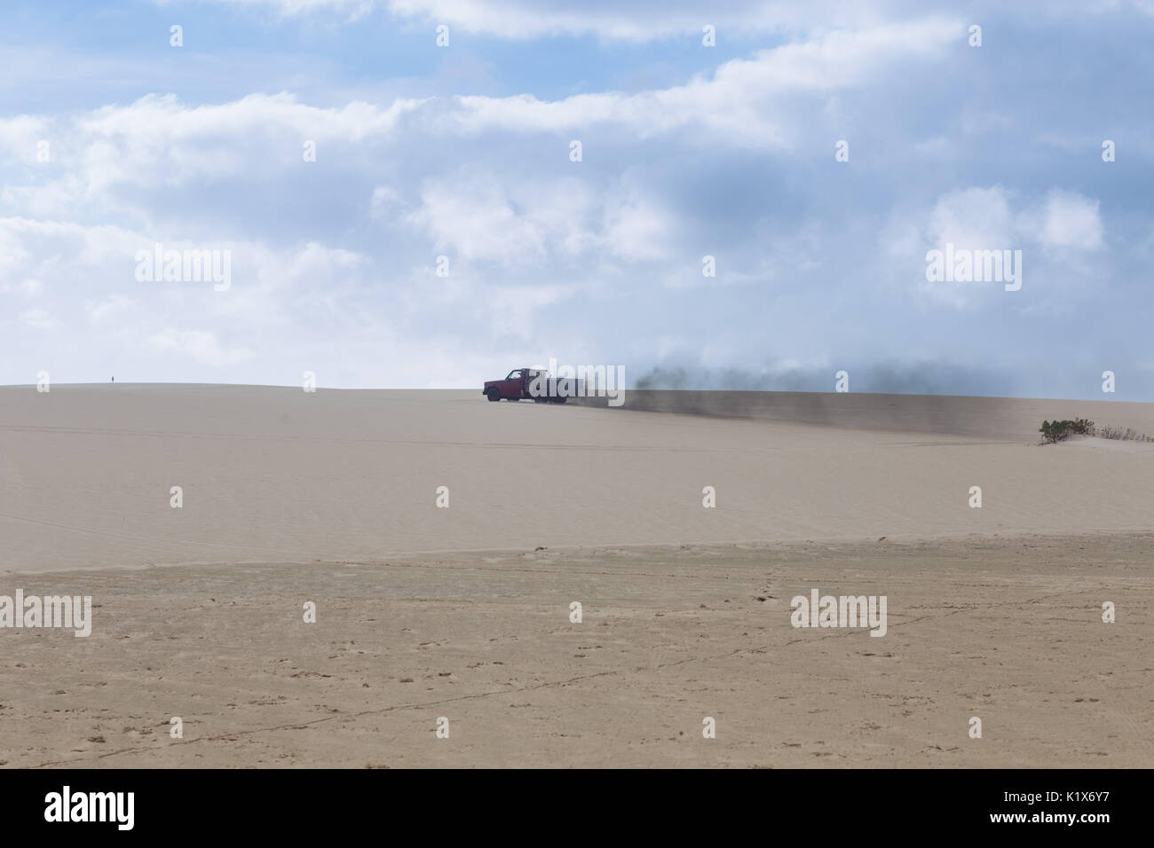An old truck expelling gas fumes smoke polluting fresh air in de dunes ...