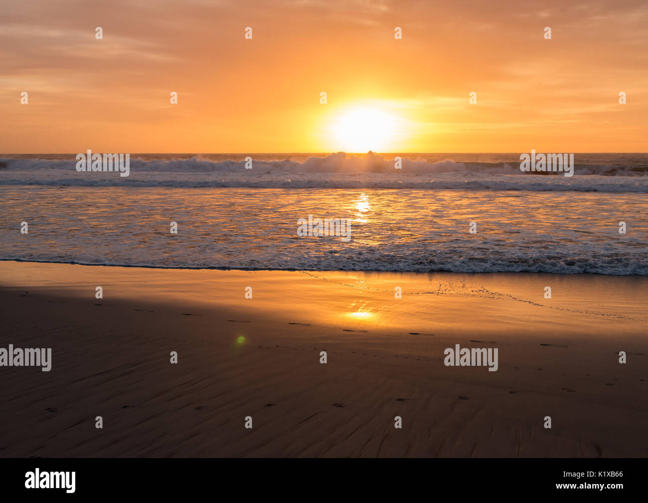 Sun Low in the Sky over beach with Foot Prints in the Sand Stock Photo ...
