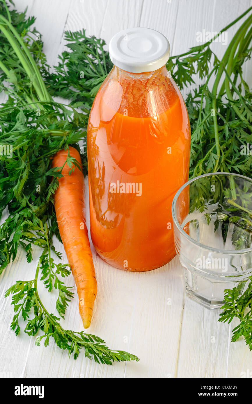 A bottle of carrot juice with empty glass and some fresh carrots on ...