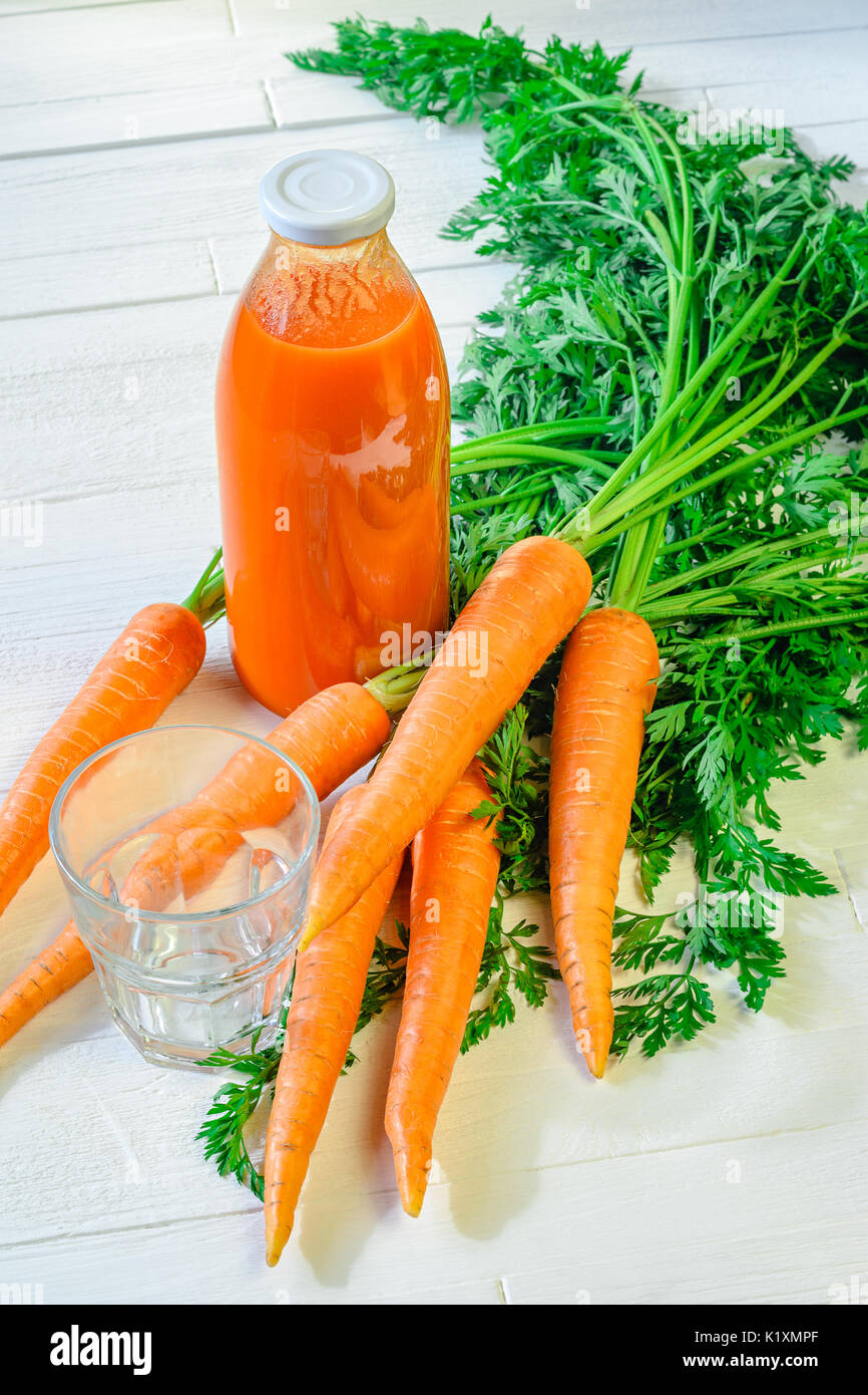 A bottle of carrot juice with empty glass and some fresh carrots on ...