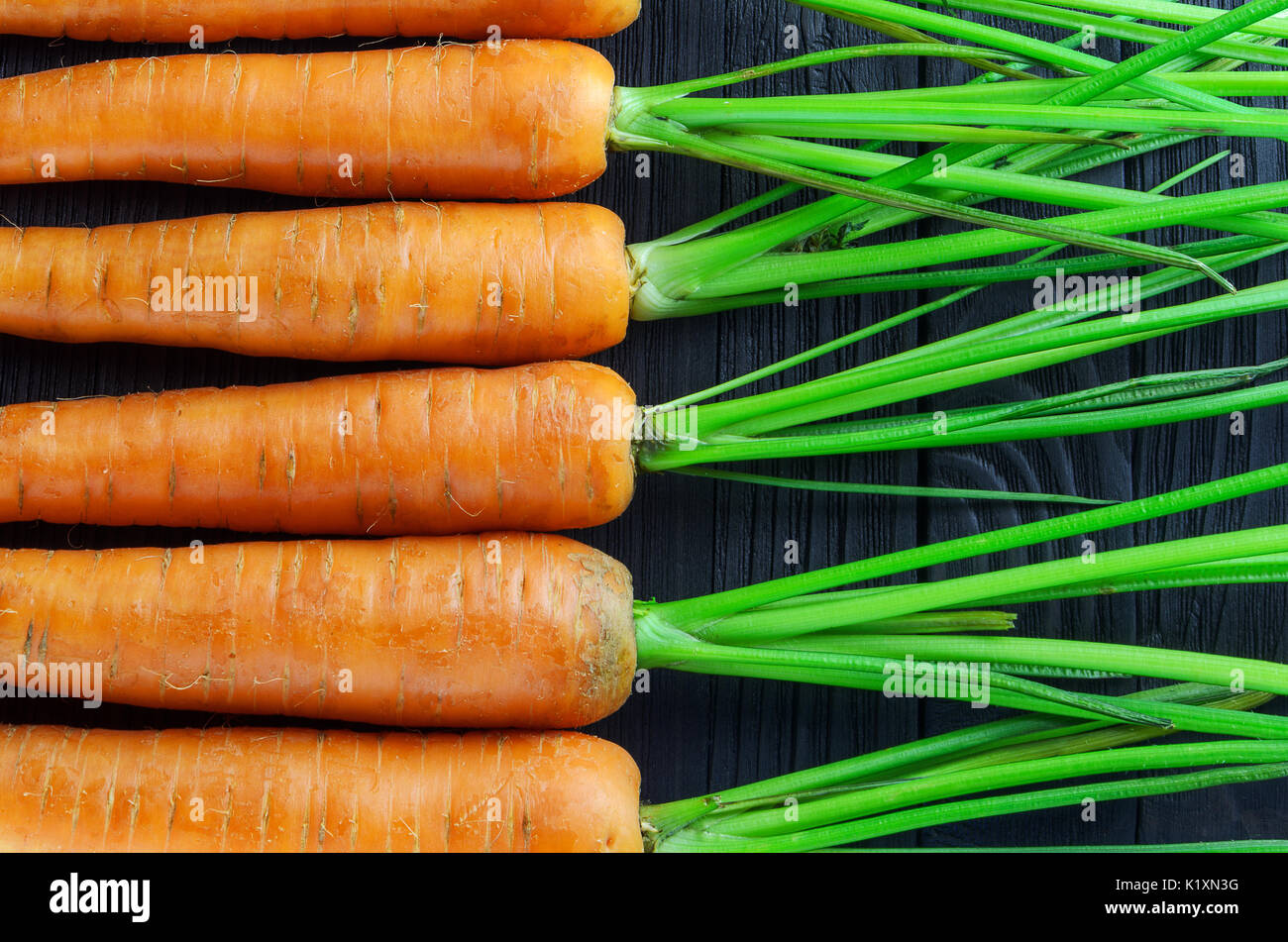 Fresh carrots densely packed near each other pattern. Carrots on black ...