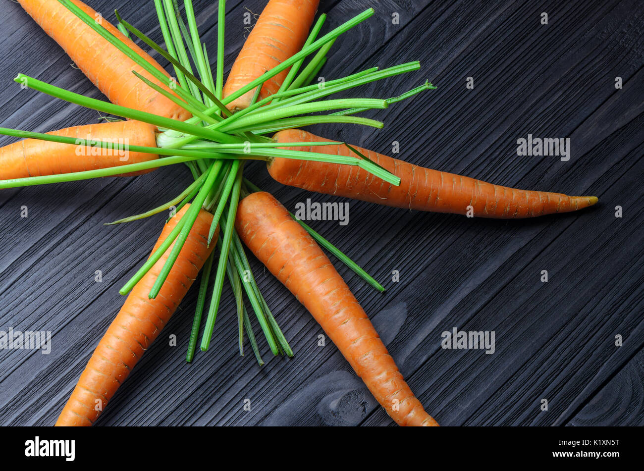 Fresh carrots carefully laid out in a geometric pattern on a black ...
