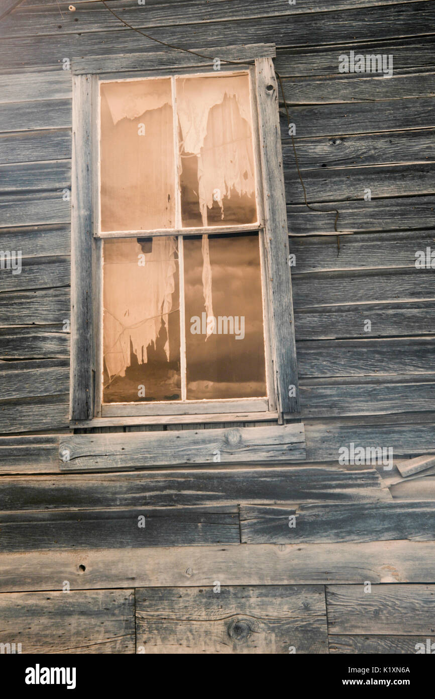 Close up of tattered curtains in window of old abandoned wooden house ...