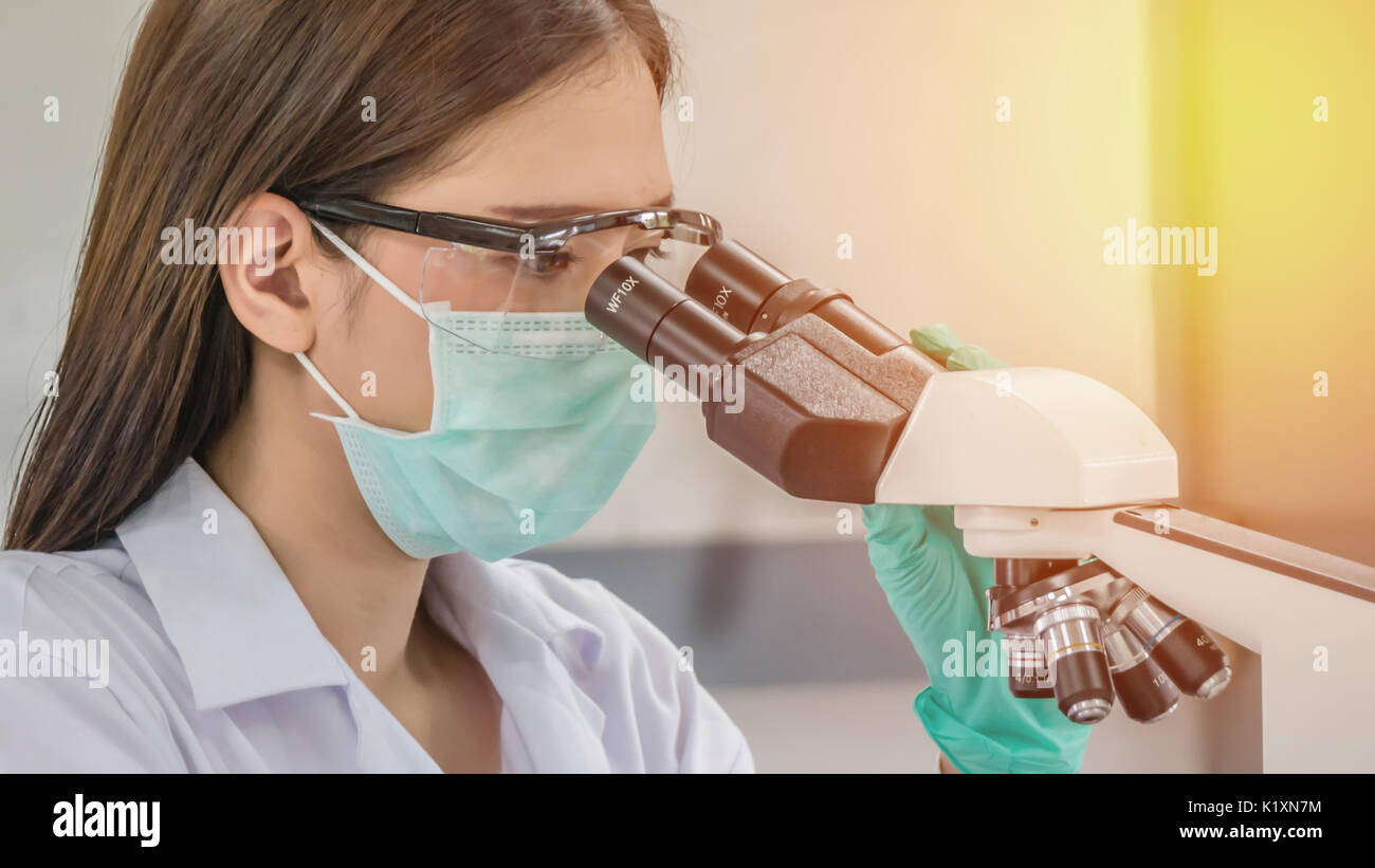 scientist looking through a microscope in a laboratory Stock Photo - Alamy