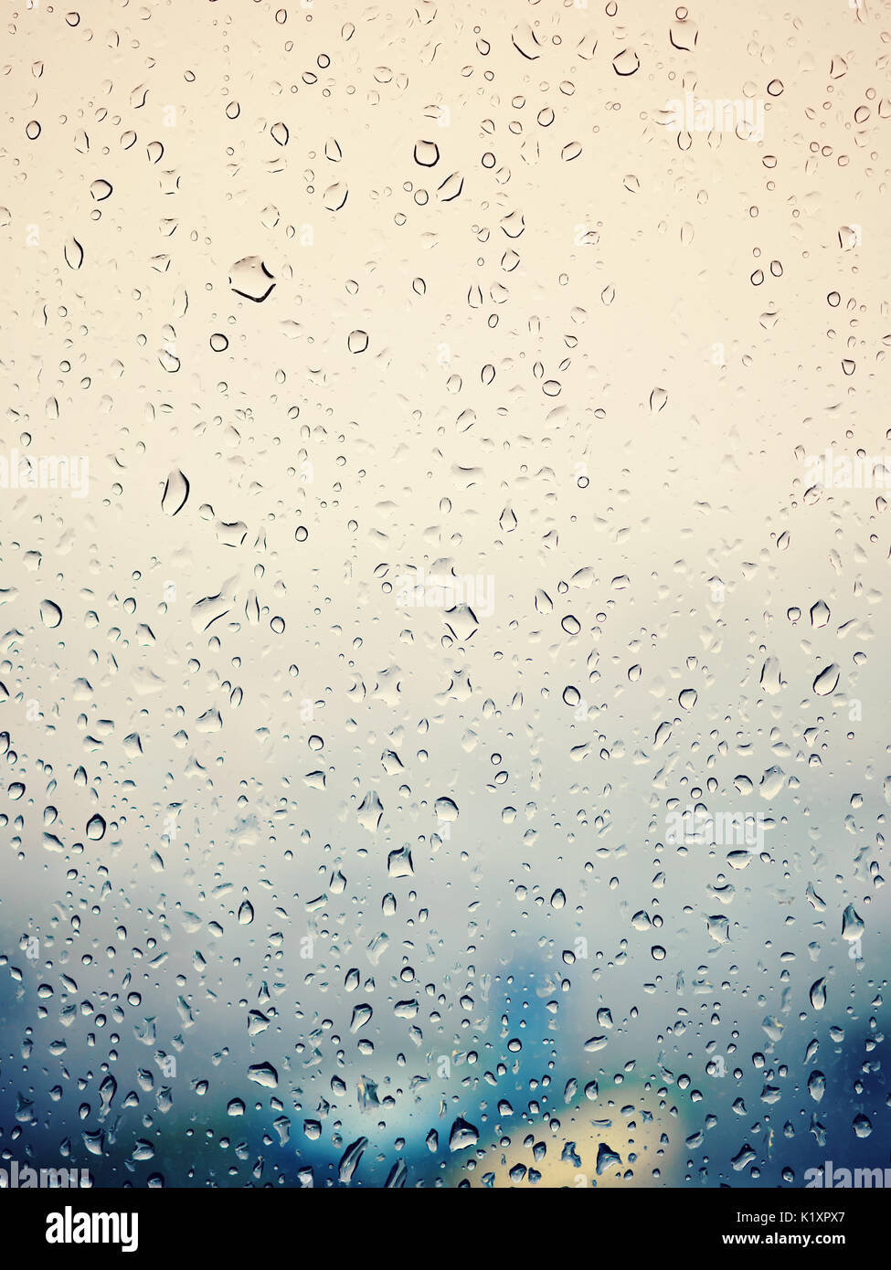 Rain in city, water drops on wet window glass, sunset. Blured background Stock Photo - Alamy