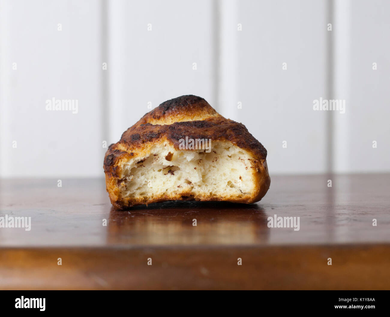 Burnt, uniced cinnamon roll with a bite taken out Stock Photo - Alamy