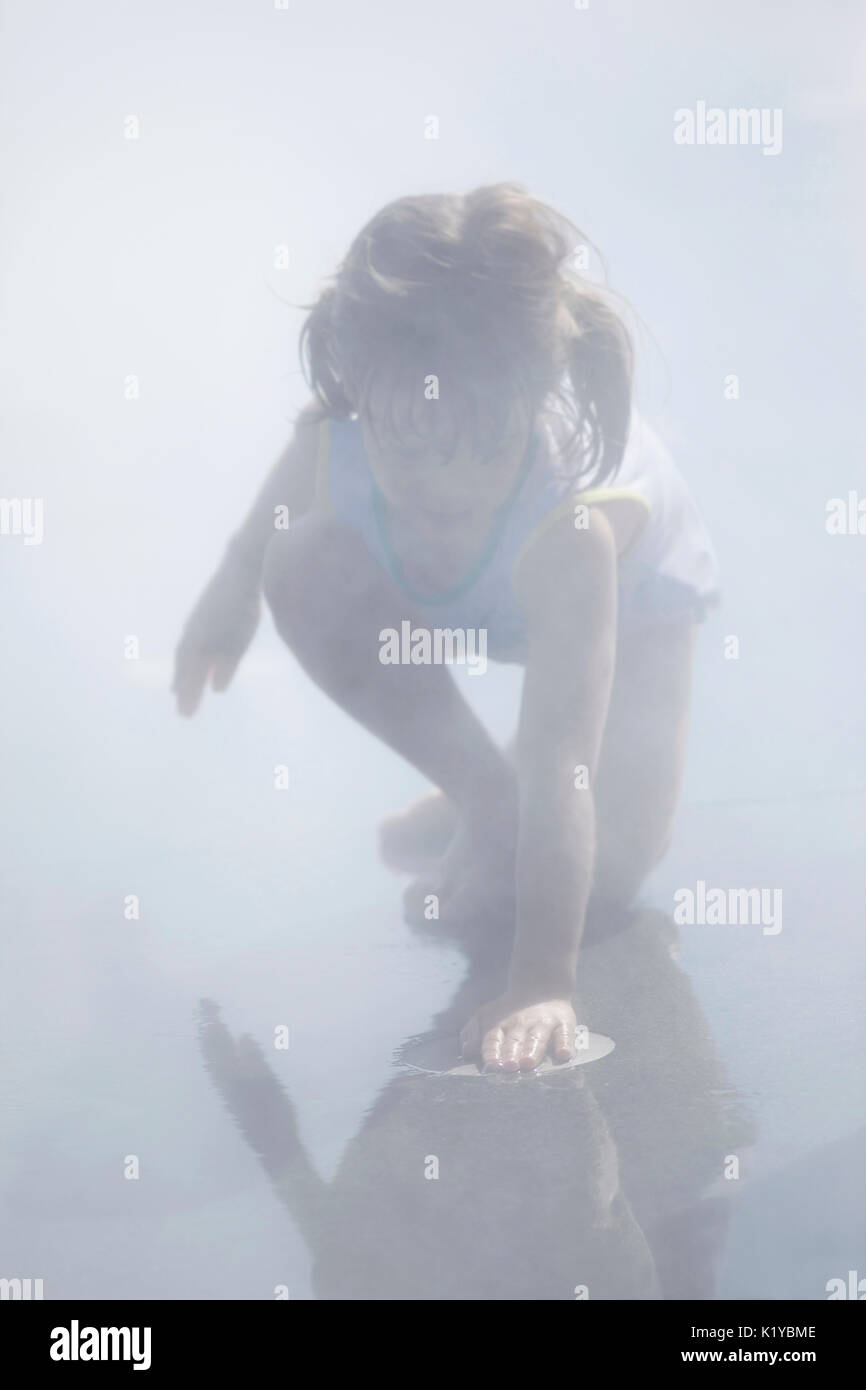 Young girl playing in mist of a basin in Summer Stock Photo - Alamy