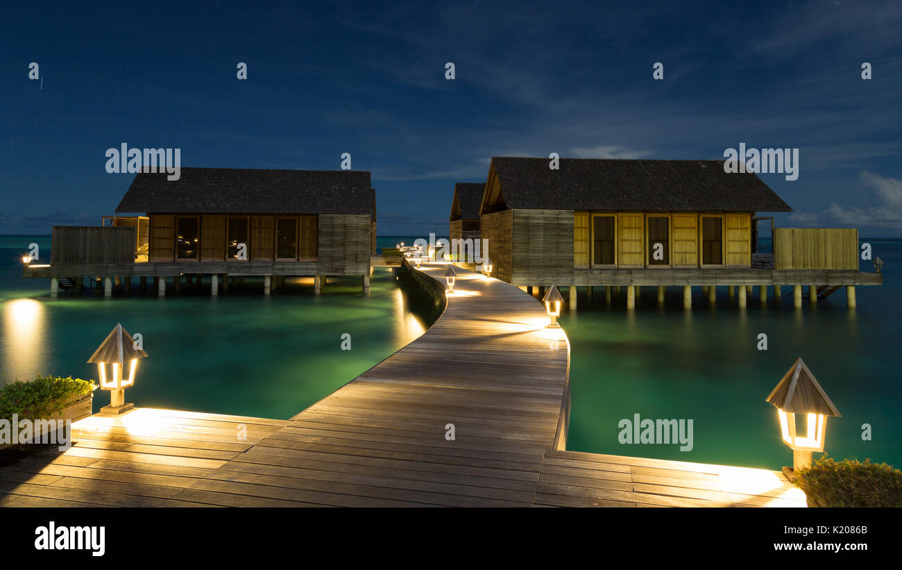 Wooden huts on stilts in lagoon at night, Gangehi Island, Ari Atoll ...