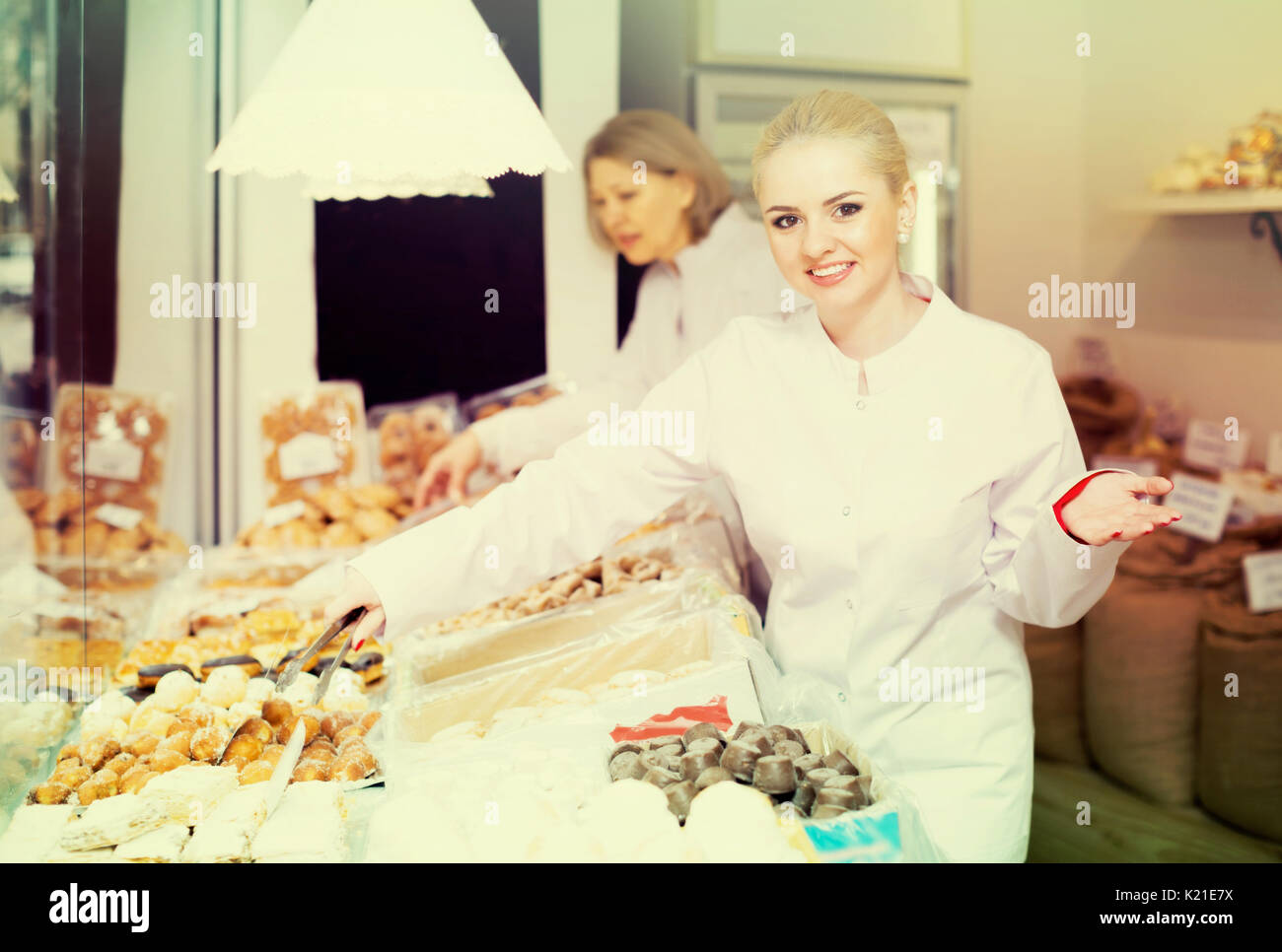 Smiling blonde woman offering fresh and tasty pastry in bakery Stock ...