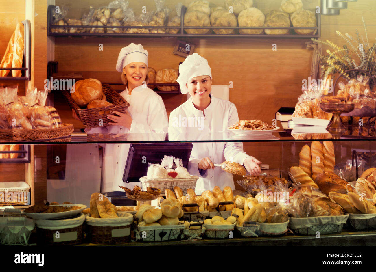Bakery staff offering bread and different pastry for sale at sweet-shop ...