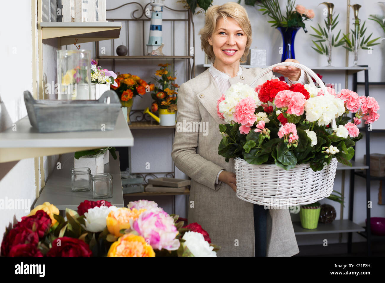 Mature female customer choosing flowers in floral department Stock ...