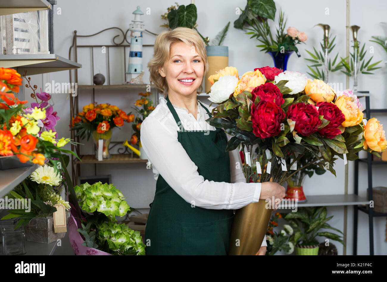 Female florist wearing an apron and happily holding big bouquet with ...