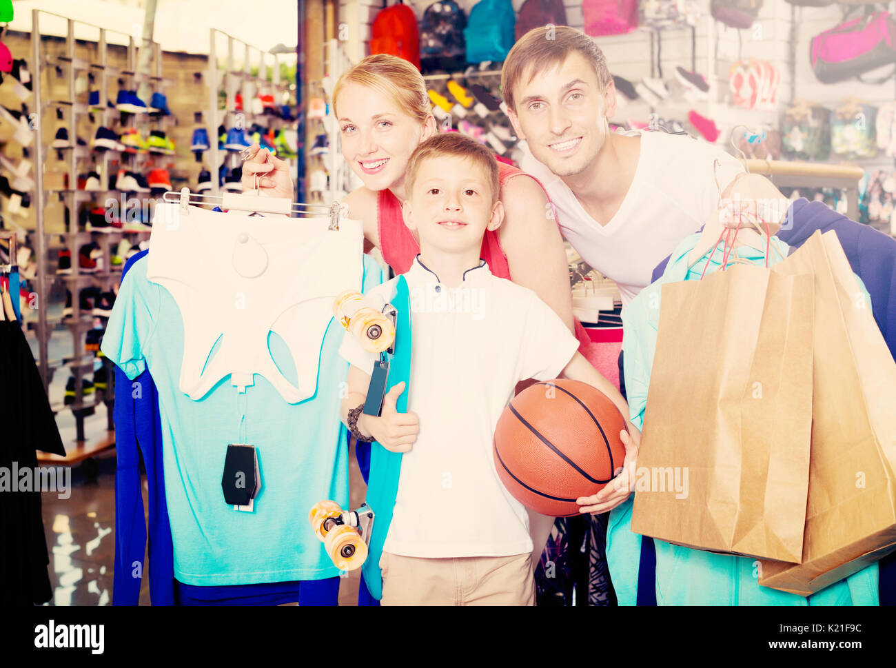 Adult smiling parents with boy in school age shopping clothing in sport ...