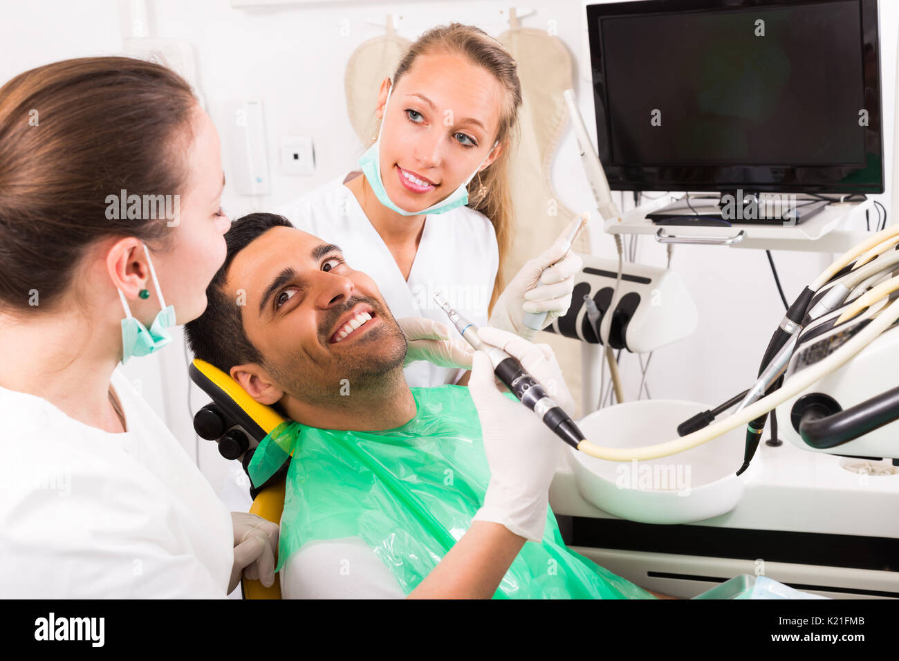 Smiling male patient and positive dental clinic crew during teeth check ...
