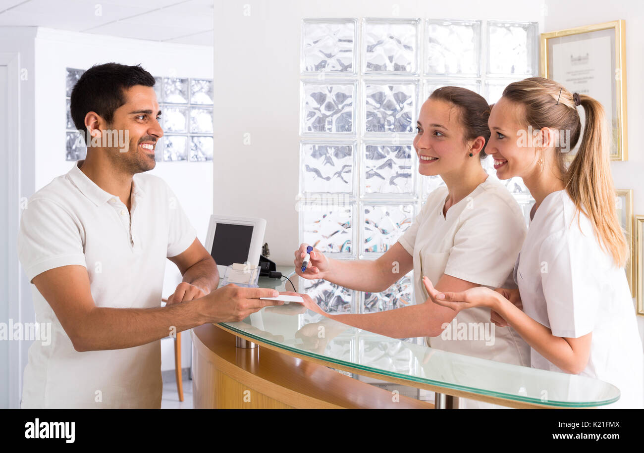 Smiling young guy talking with cheerful young nurses in medical clinic ...