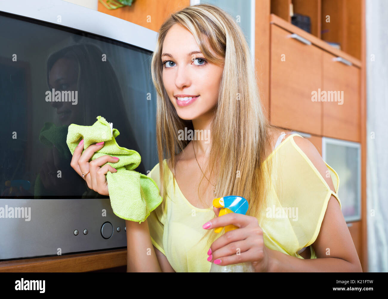 Blonde smiling girl cleaning TV with rag at home Stock Photo - Alamy
