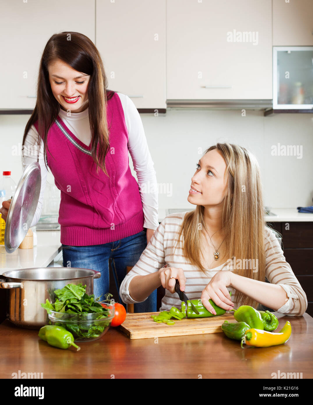 Two young women cooking together at them kitchen Stock Photo - Alamy