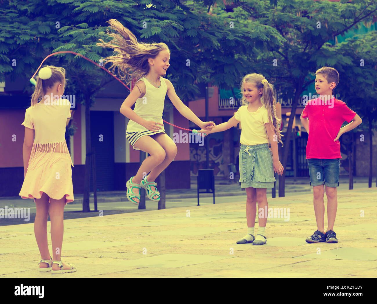 portrait of happy children skipping together with jumping rope on urban ...