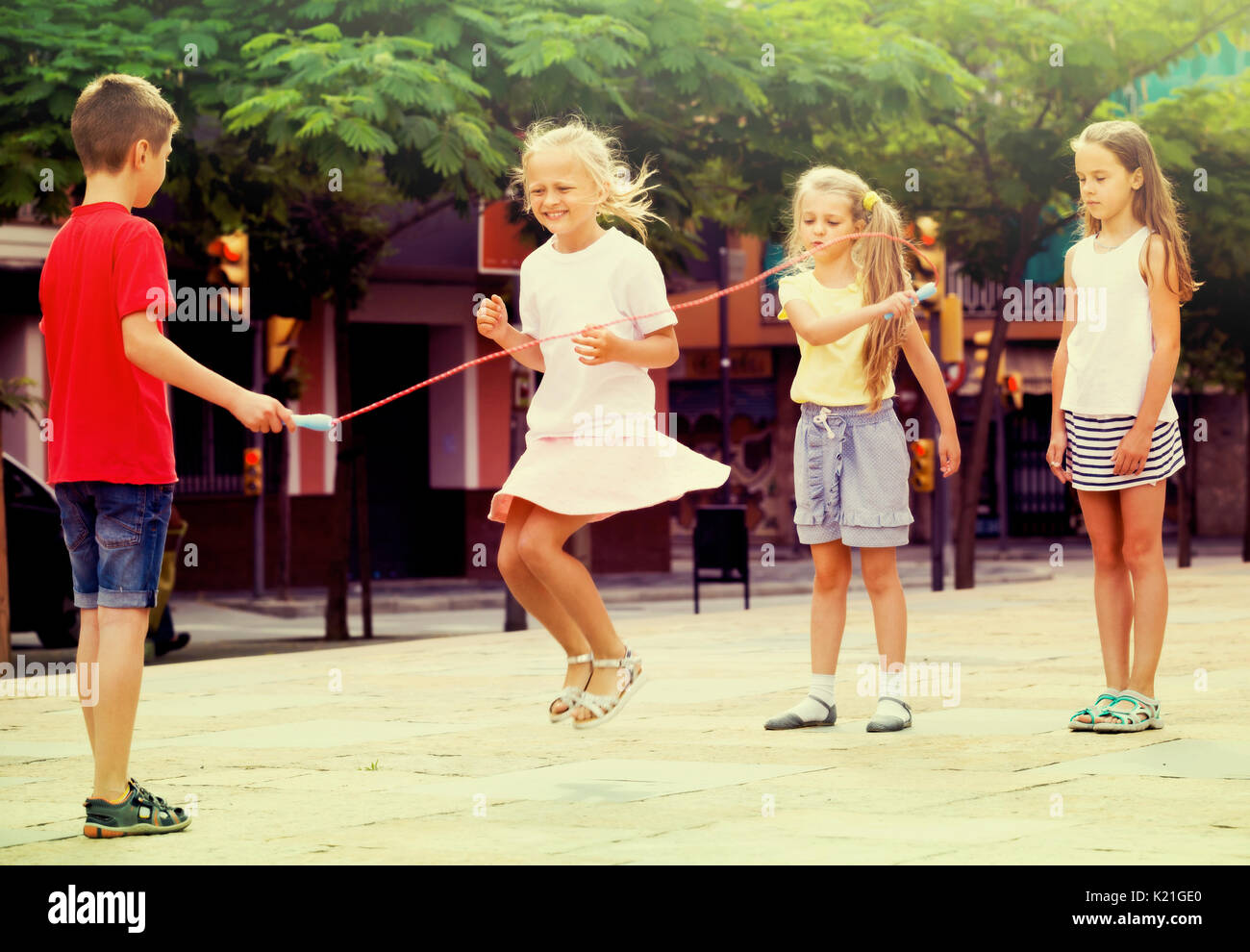 portrait of joyful children skipping together with jumping rope on ...