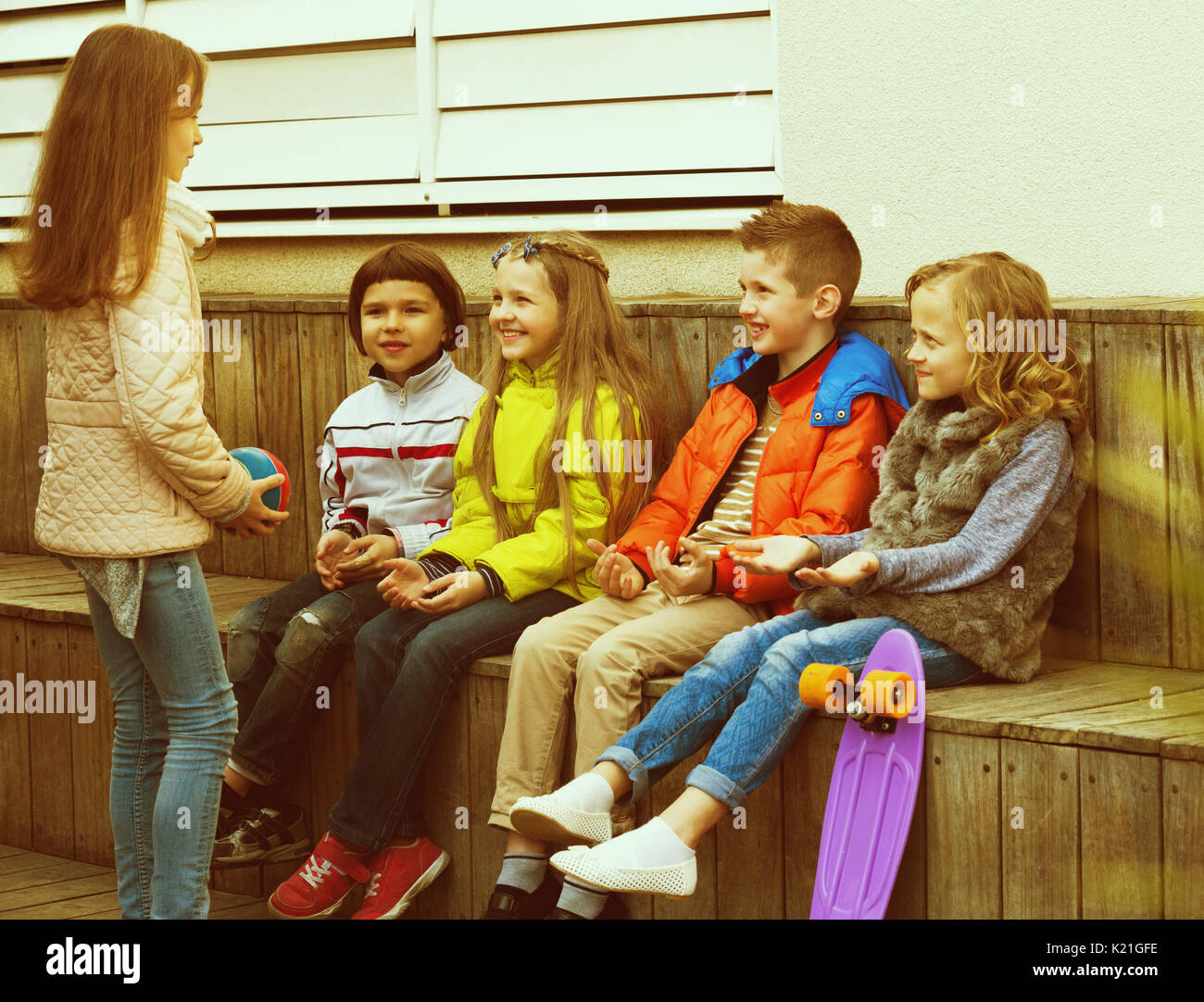 Group of children sitting on bench and playing with ball Stock Photo ...