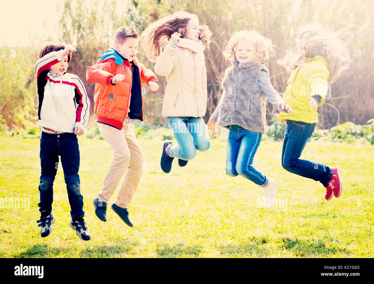 Happy smiling kids having fun and jumping up in spring field Stock ...