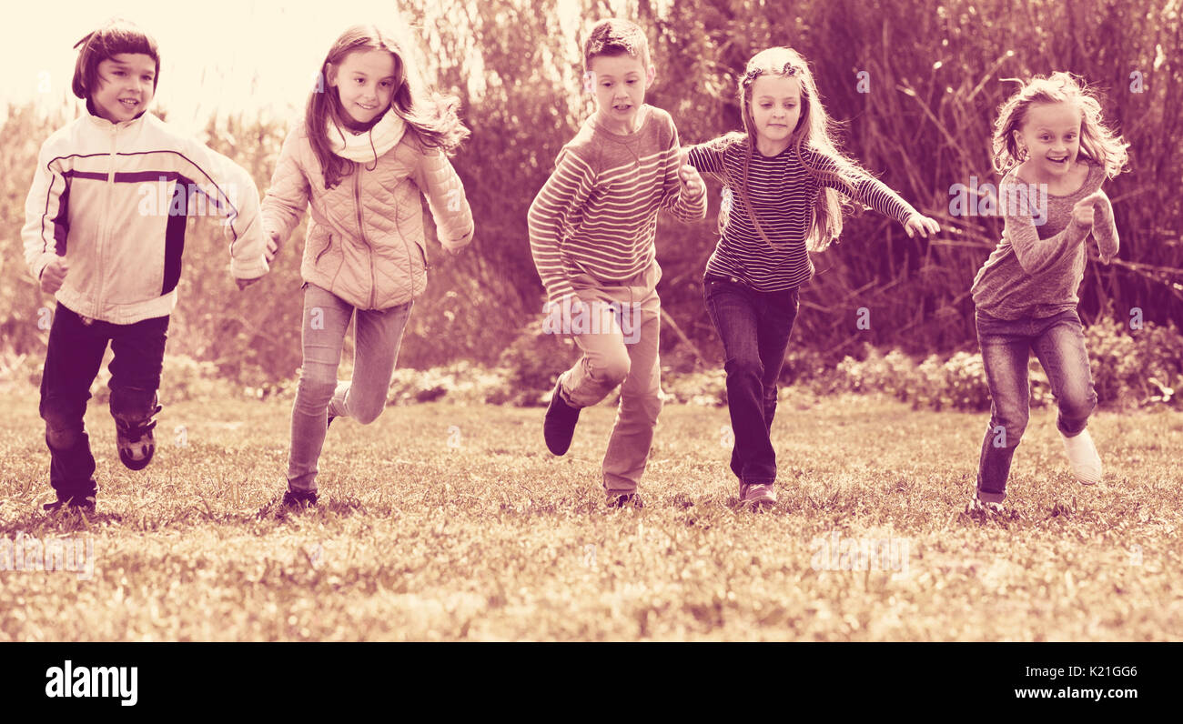Excited kids full of energy run in race through field Stock Photo - Alamy