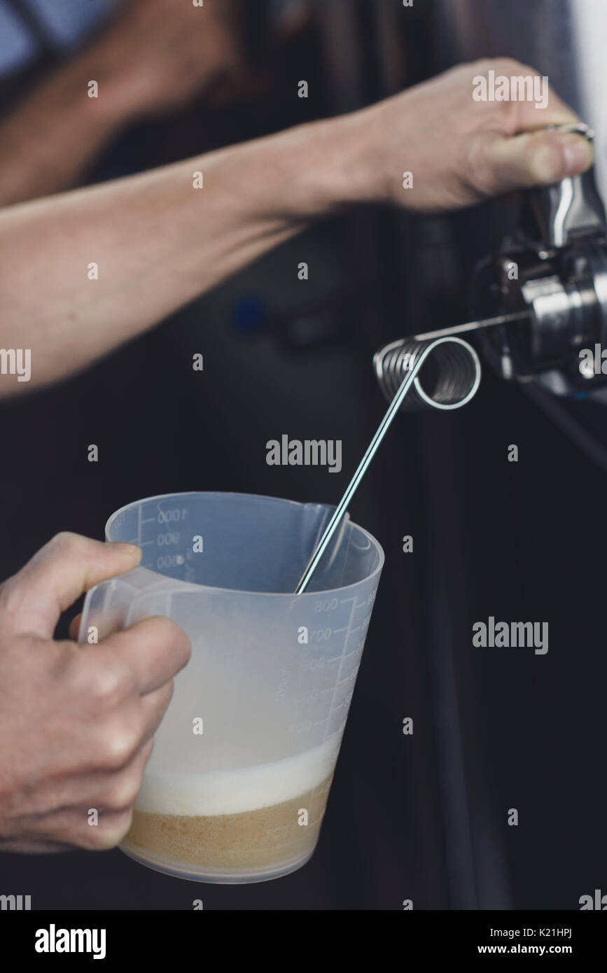 Hands of brewery worker pouring beer from the tank to plastik pitcher ...