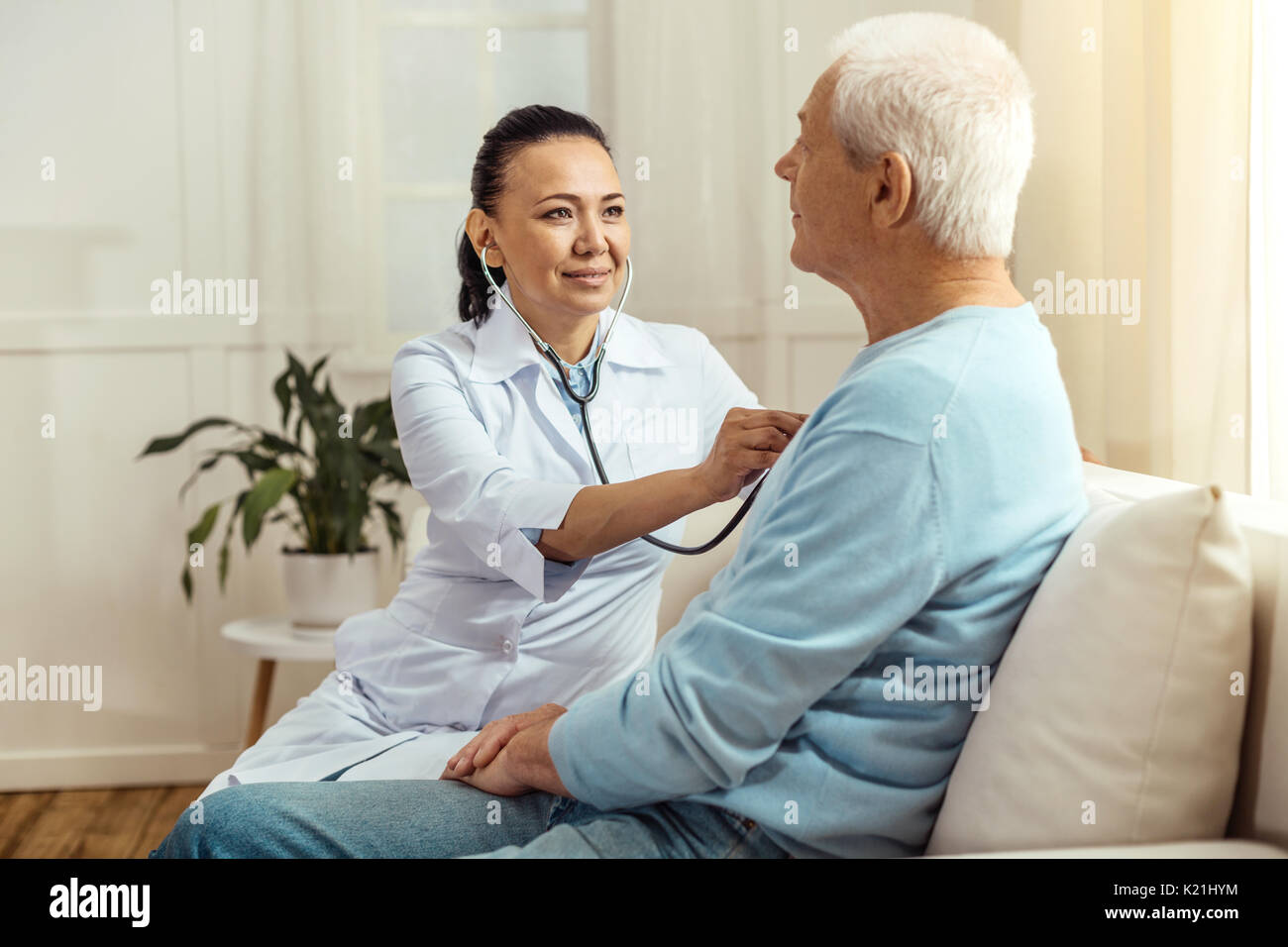 Smart cheerful nurse using stethoscope Stock Photo - Alamy