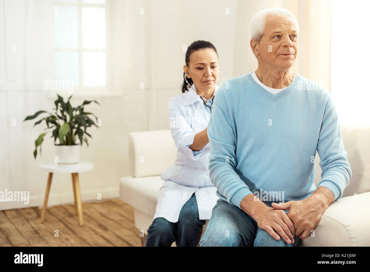 Smart serious doctor sitting behind her patient Stock Photo - Alamy