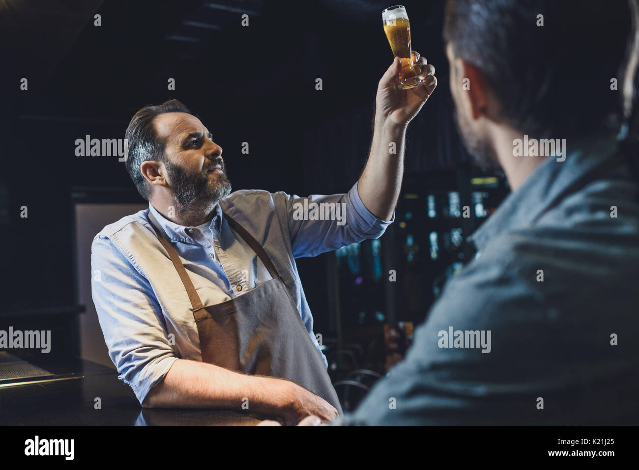 Male brewery worker examining small glass of beer Stock Photo - Alamy