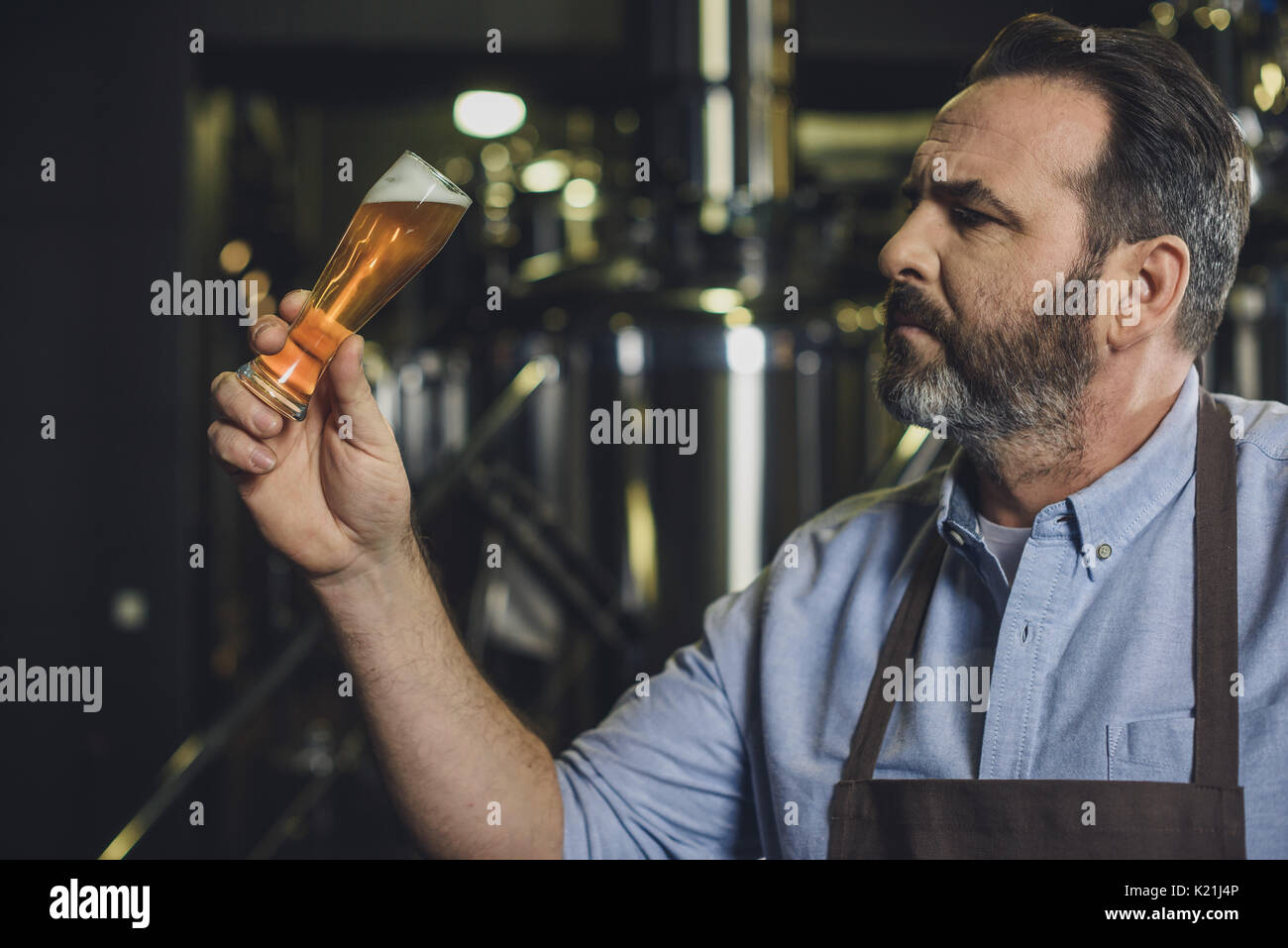 Male brewery worker examining small glass of beer Stock Photo - Alamy