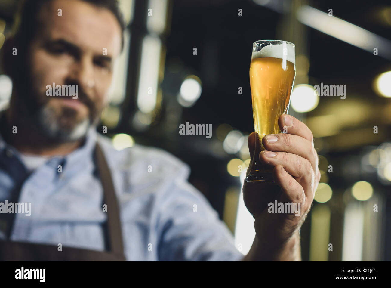 Male brewery worker examining small glass of beer Stock Photo - Alamy