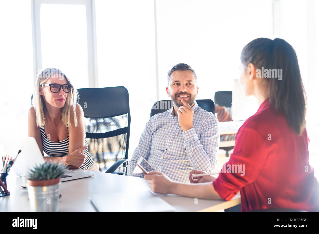 Three business people in the office talking together Stock Photo - Alamy