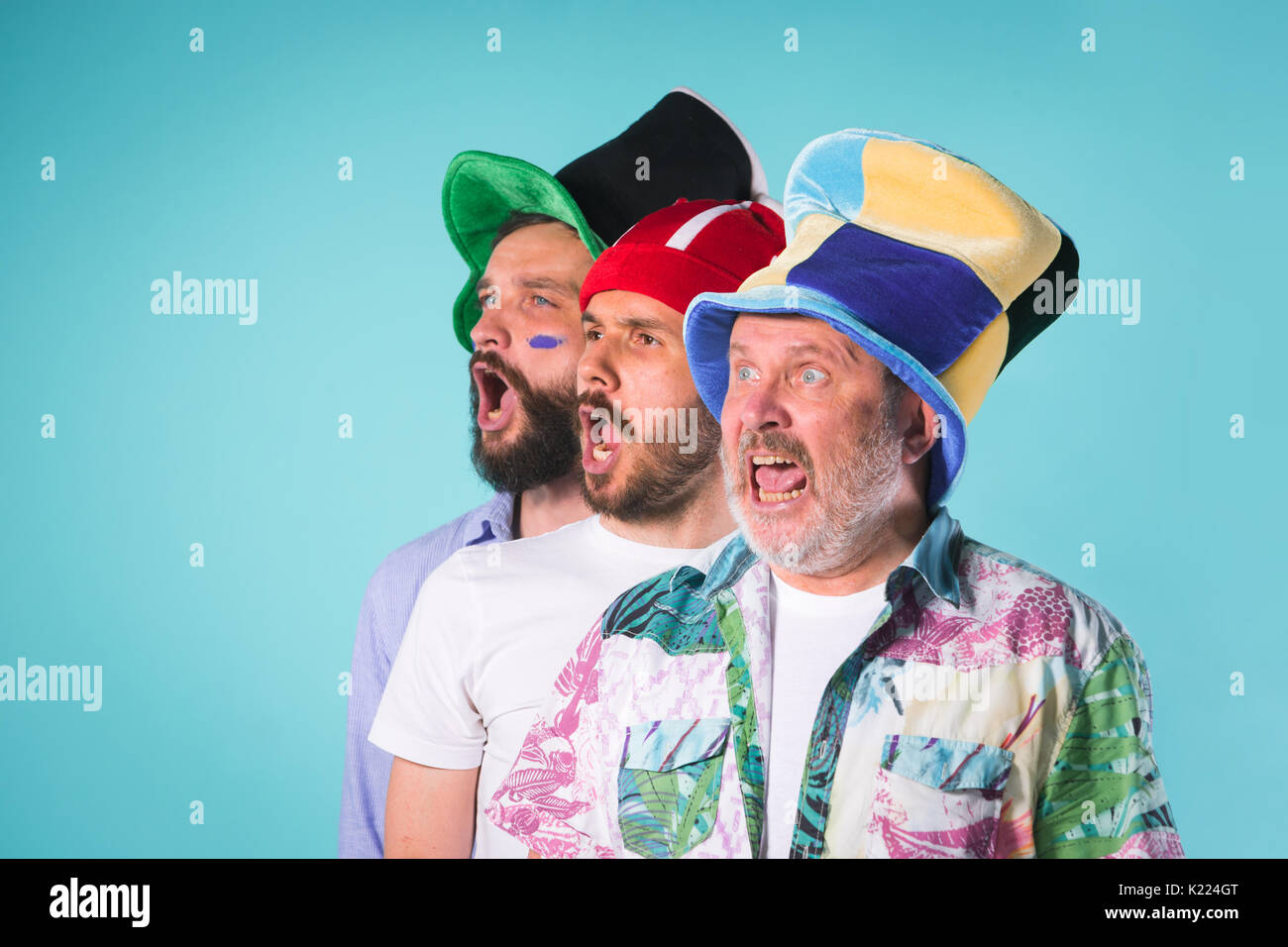 The three football fans singing the national anthem over blue Stock ...