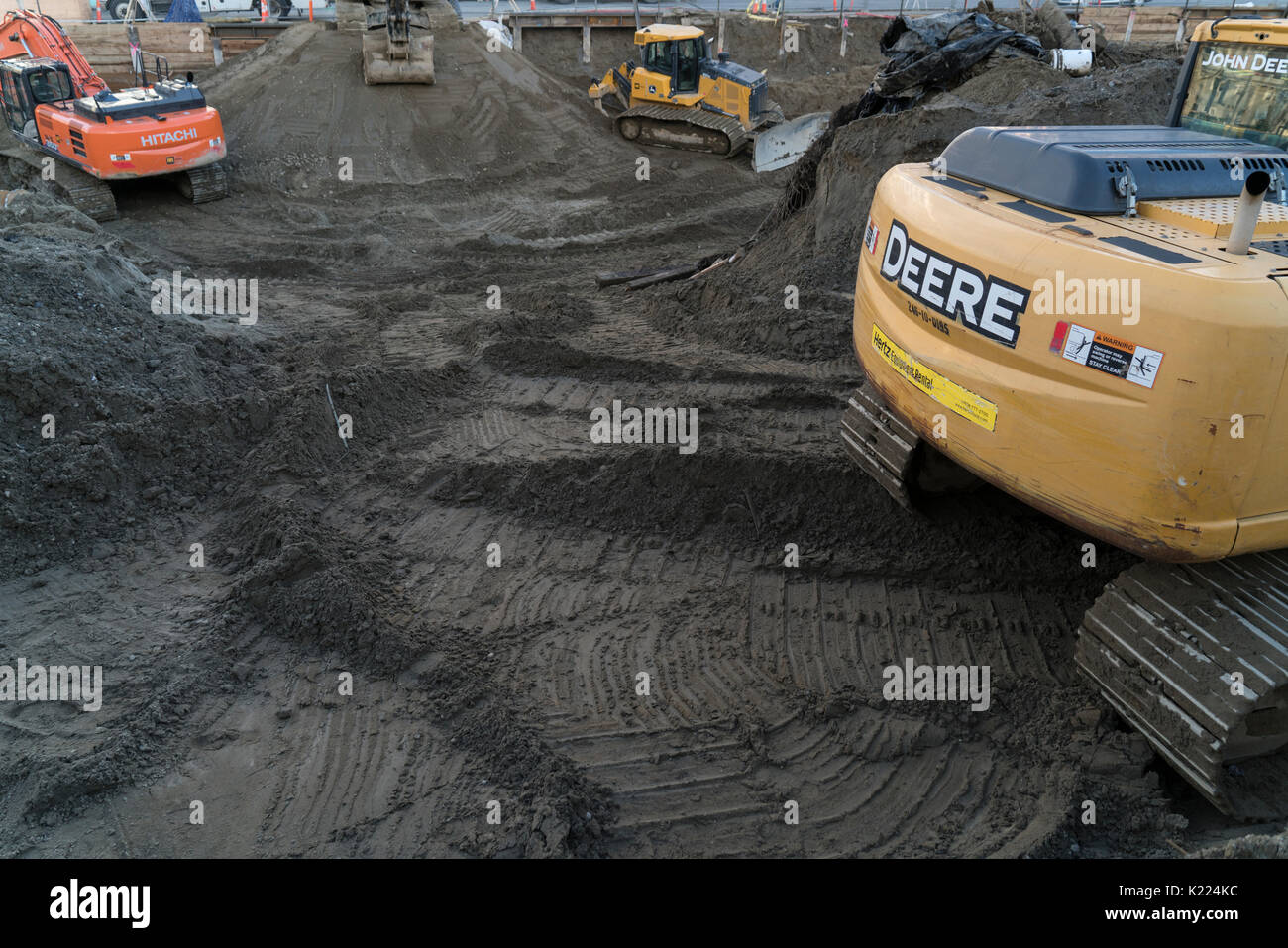 Earth moving machines on site digging a hole in the ground for a ...