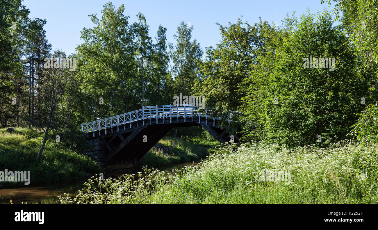 A wooden white bridge in the environment. Flowers and trees in the ...