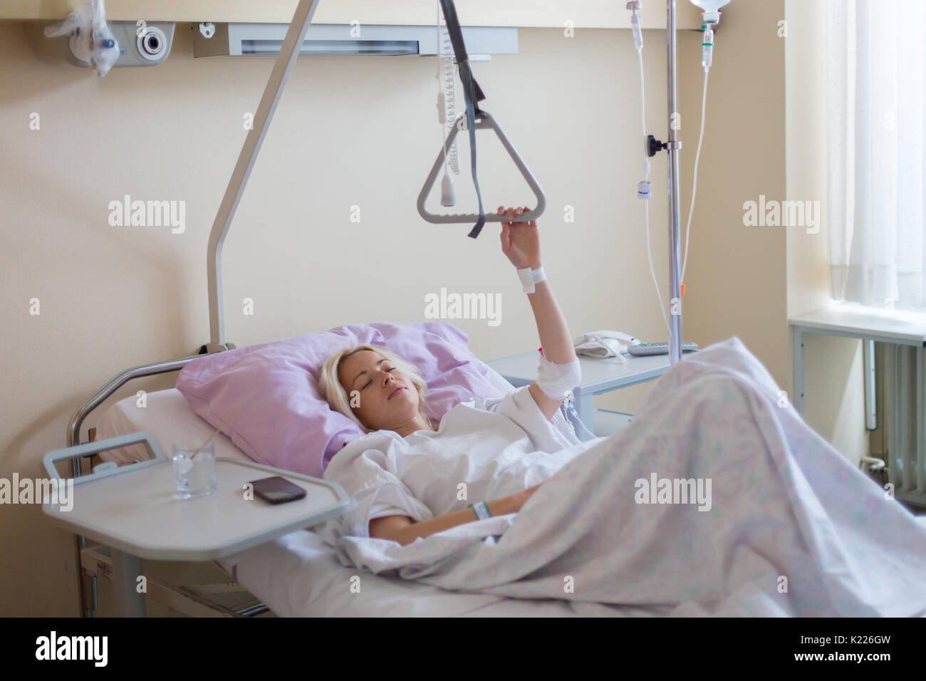 Bedridden female patient recovering after surgery in hospital care ...