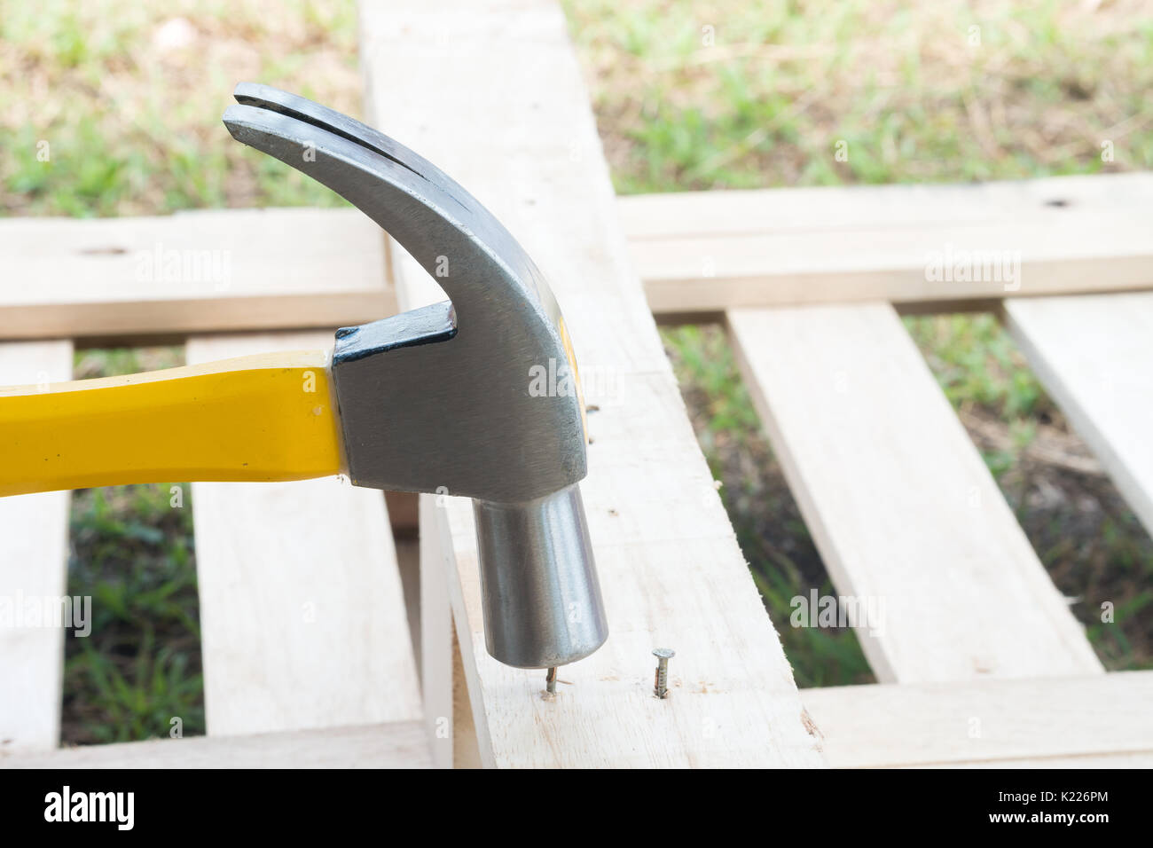 Yellow hammer and Nail Using hammer and nail on wood Stock Photo - Alamy