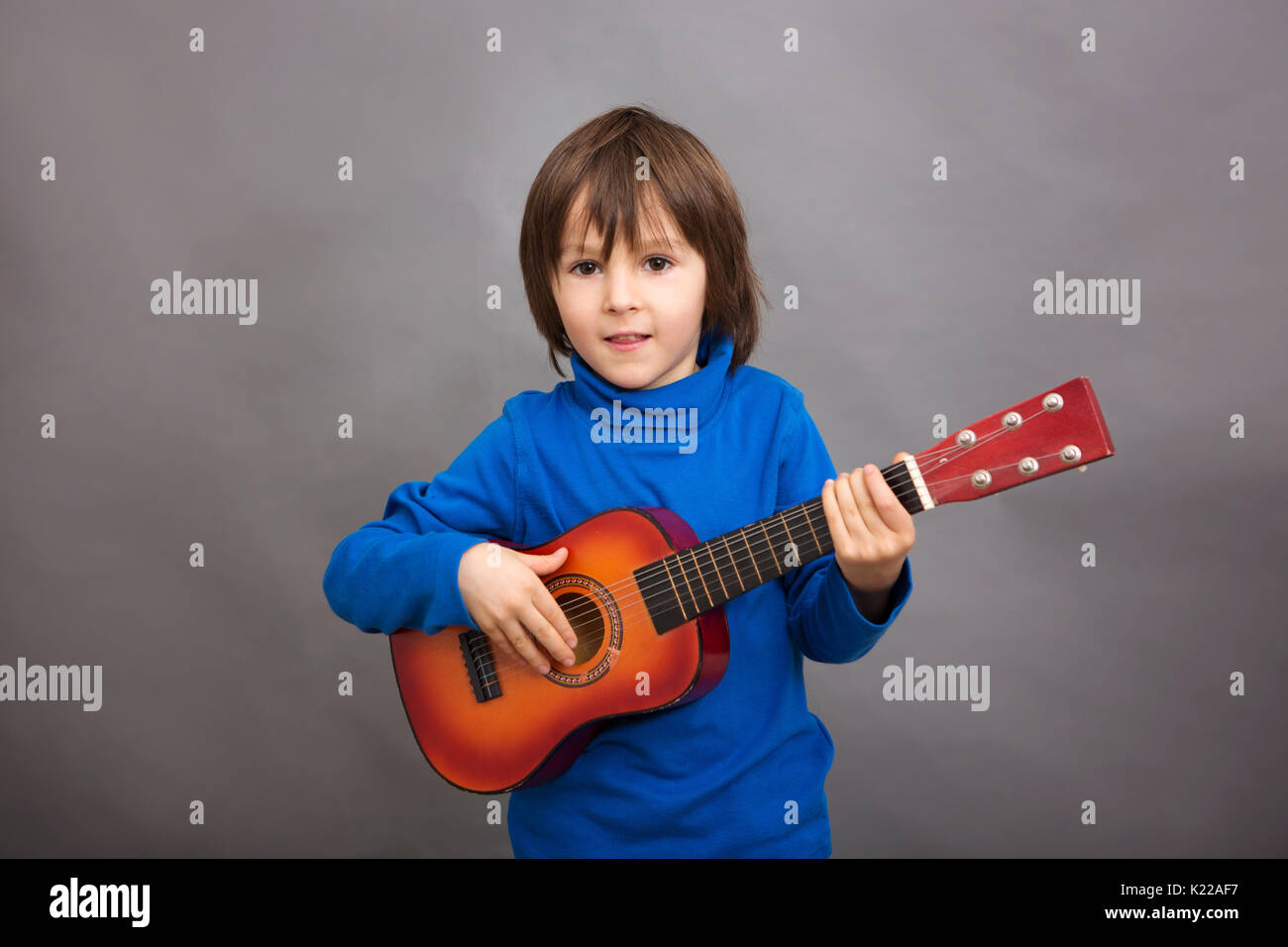 Preschool child, playing little guitar, isolated image, studio shot ...